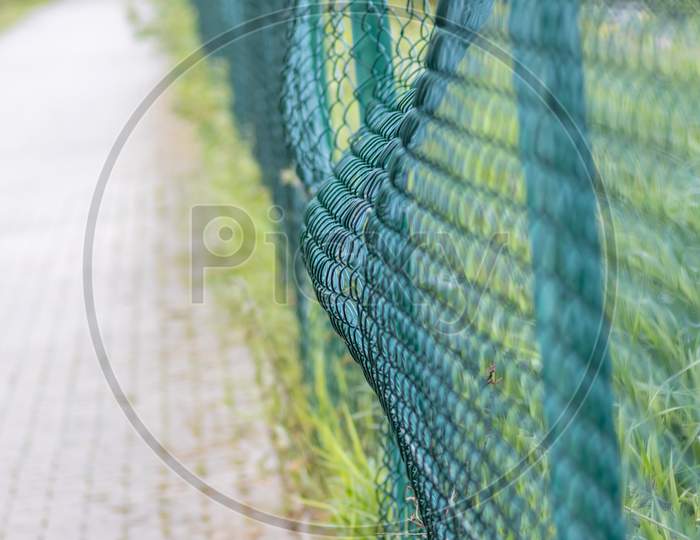 Image of Green damaged wire-mesh fence is ruined after collision with ...