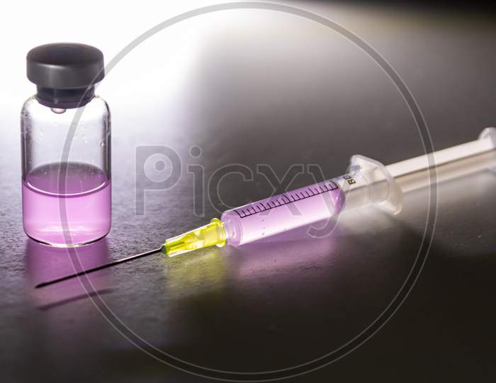 Image of Pink drug in an ampulla ready for injection with a syringe to ...