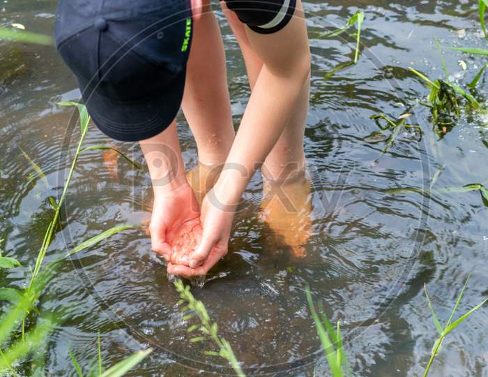 Image of Young boy playing barefoot with clear water at a little creek ...