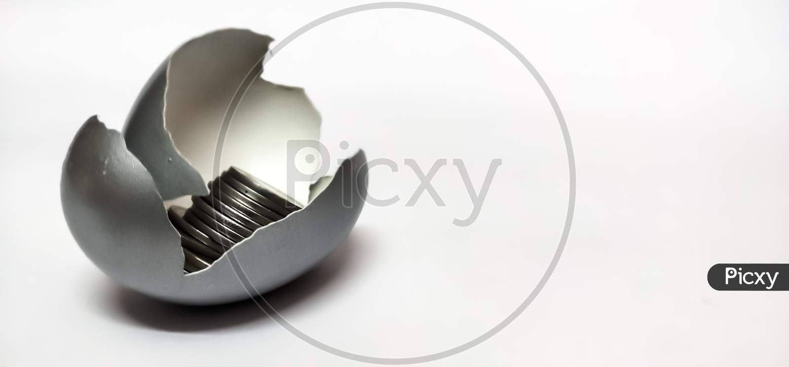 Image of Closeup of Broken silver egg with coins inside isolated in a ...