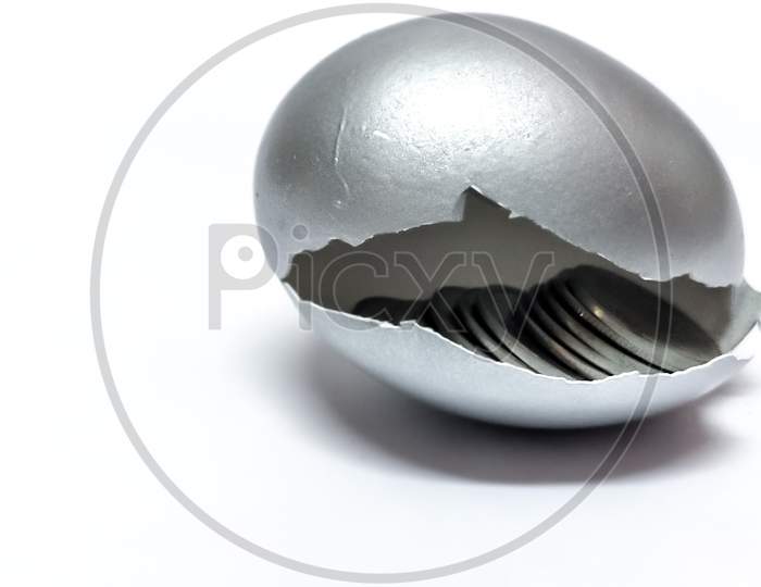 Image of Closeup of Broken silver egg with coins inside isolated in a White background with ...