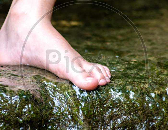 Image of Young boy playing barefoot with clear water at a little creek ...