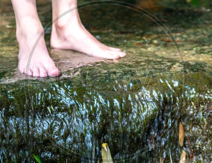 Image of Young boy playing barefoot with clear water at a little creek ...