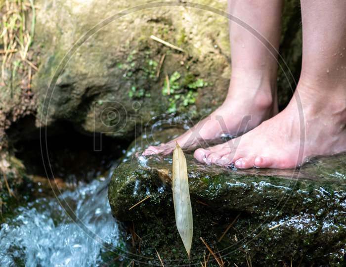 Image of Young boy playing barefoot with clear water at a little creek ...