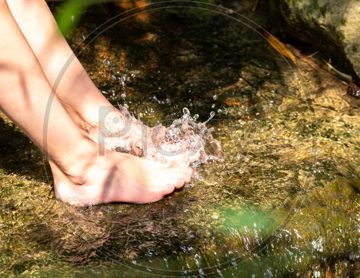 Image of Young boy playing barefoot with clear water at a little creek ...