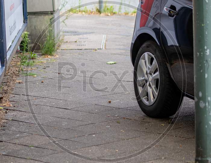 Image of Badly parked car with tire on pavement shows wheel on walkway ...