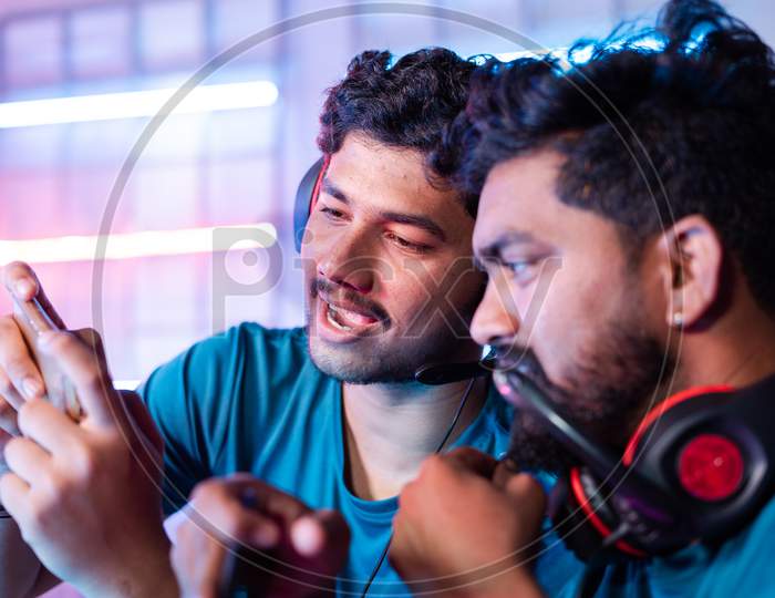 Image of Two Gamers Discussing About Game Play By Looking Into Mobile ...