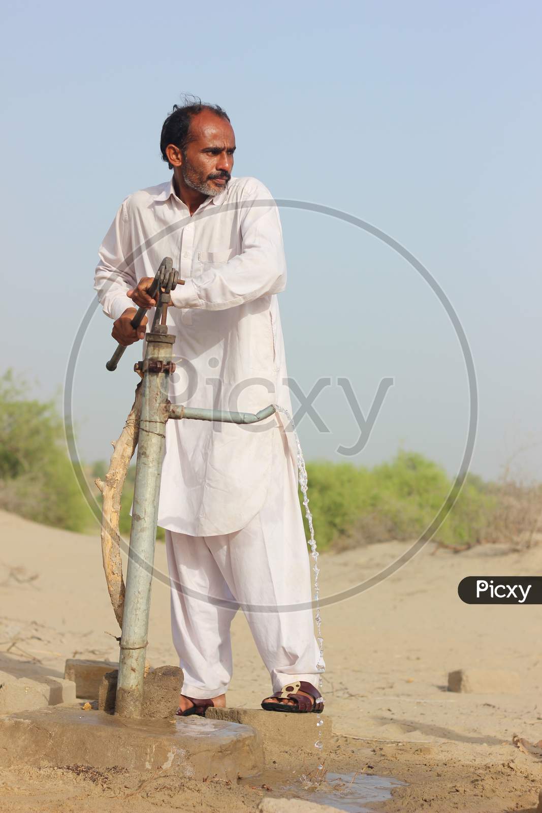 Image of Village men use a water hand pump. tharparkar area, Sindh province, Southern Pakistan ...